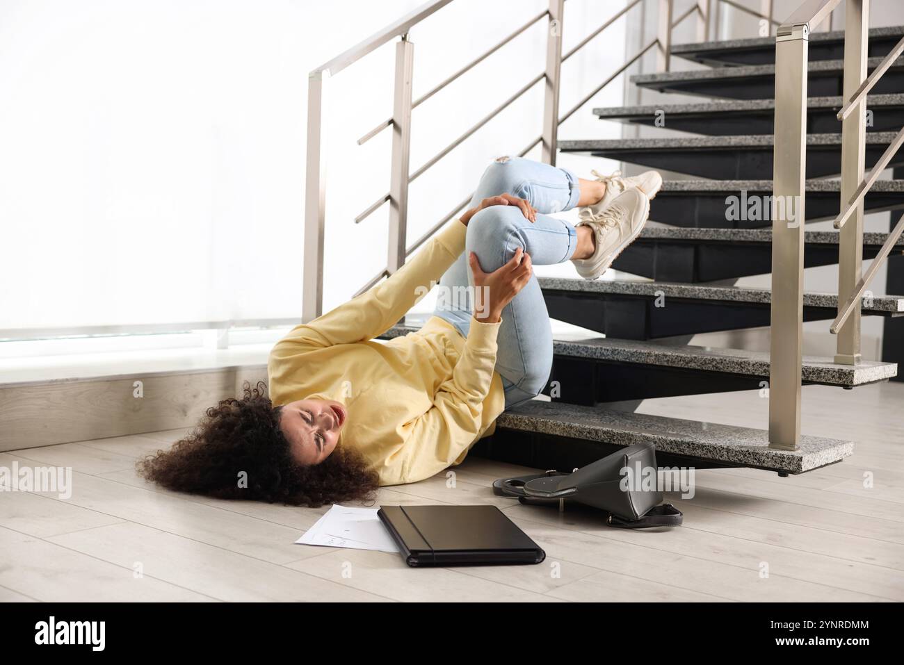 Woman with injured knee on stairs in building after fall. Dangerous ...
