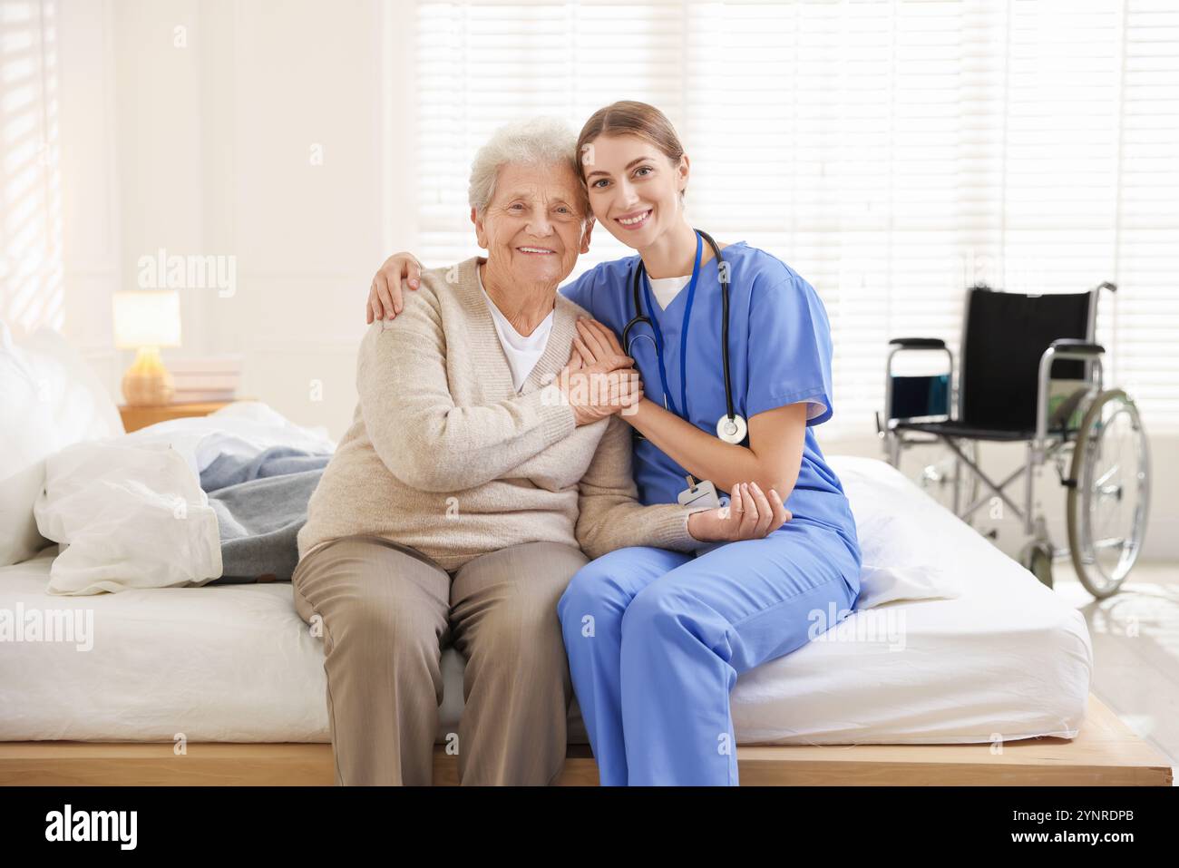 Caregiver supporting senior woman on bed indoors. Home health care service Stock Photo - Alamy