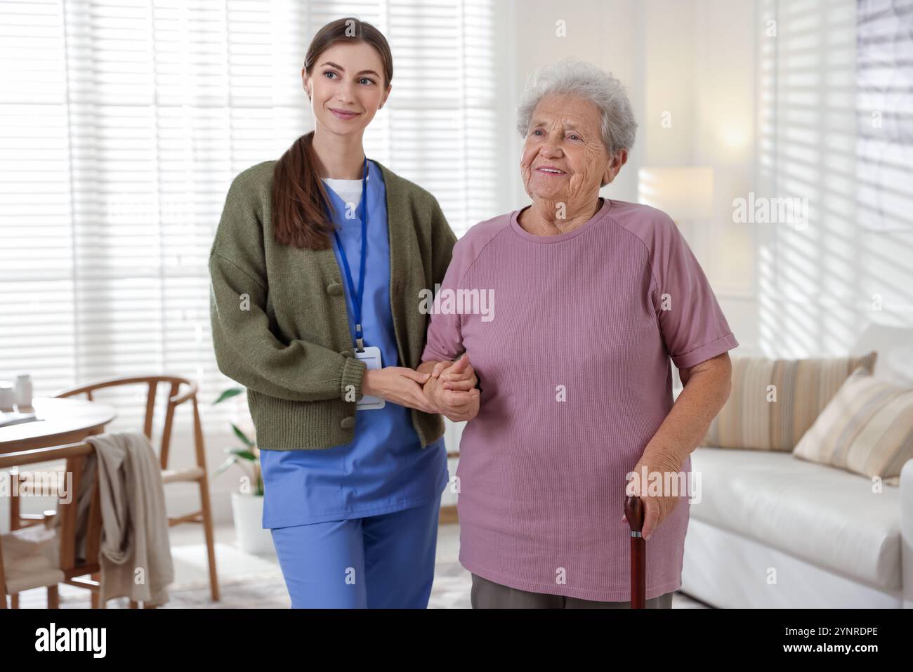 Caregiver assisting senior woman with walking cane indoors. Home health care service Stock Photo ...
