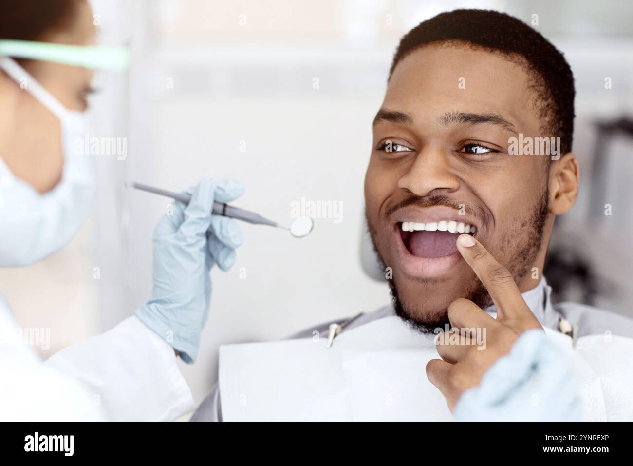 Black Male Patient Showing Aching Tooth During Check Up With Female ...