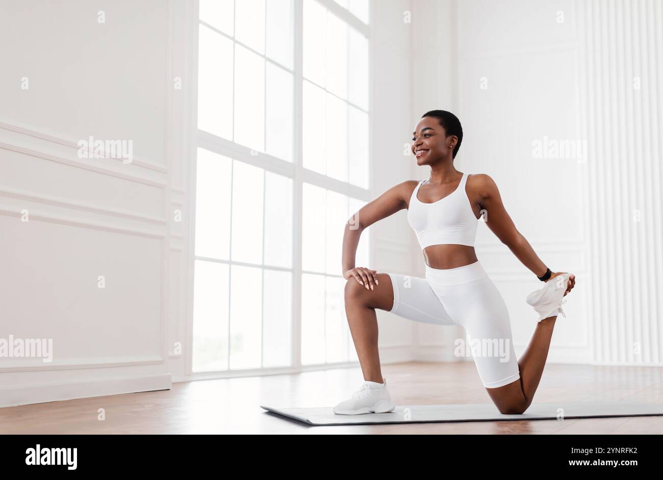 Young black woman stretching leg exercising on yoga mat Stock Photo - Alamy