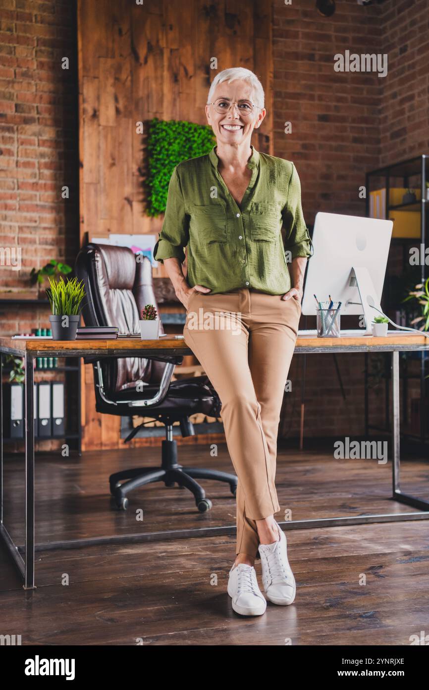 Photo of charming lovely positive lady standing modern workplace ...