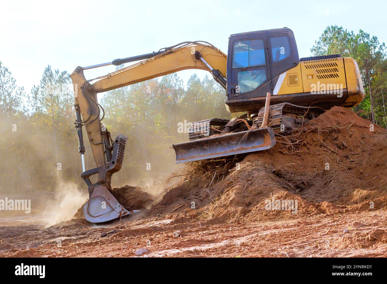 An excavator is actively digging into pile of earth at construction ...