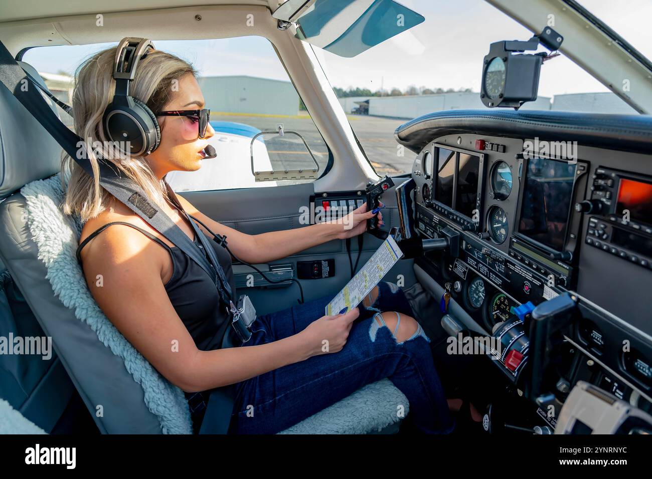 A young woman pilot diligently performs pre-flight checks beside her ...