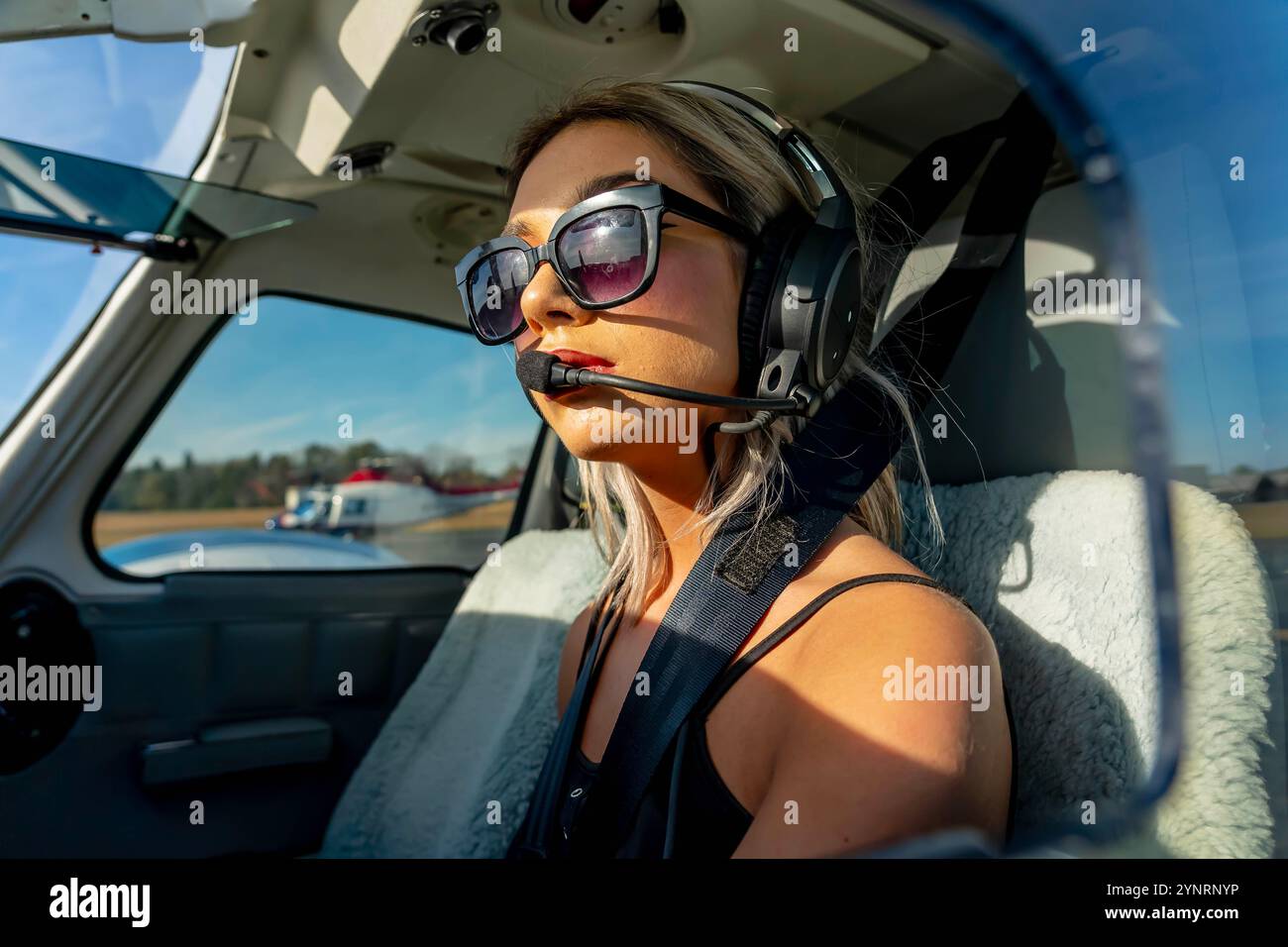A young woman pilot diligently performs pre-flight checks beside her ...