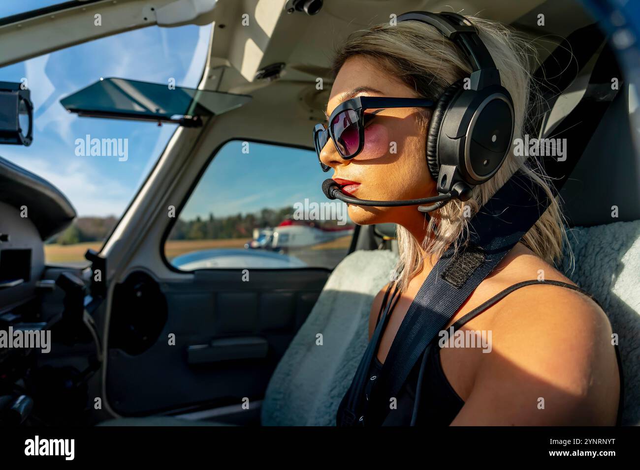 A young woman pilot diligently performs pre-flight checks beside her ...