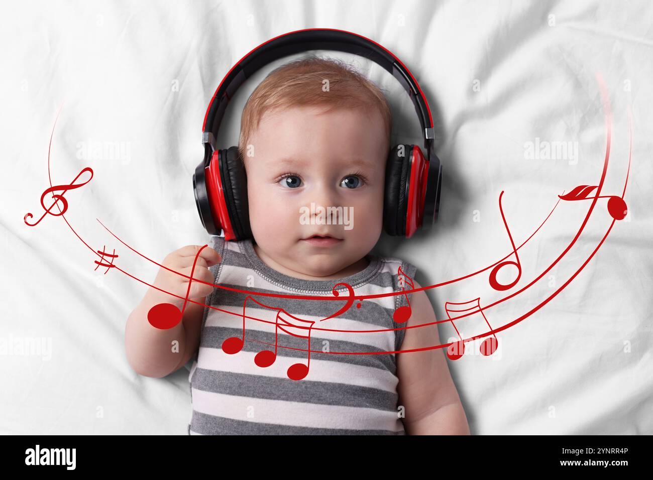 Cute little baby with headphones lying on bed, top view. Music notes ...