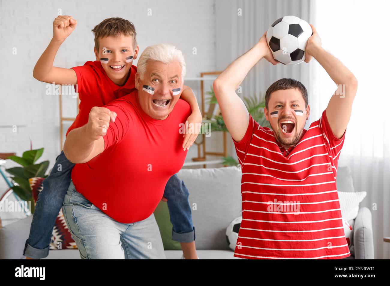 Man with his father and son cheering for football team with soccer ball ...
