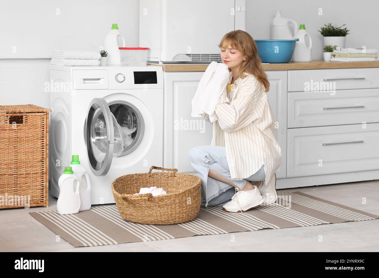 Young woman smelling clean laundry from washing machine at home Stock ...