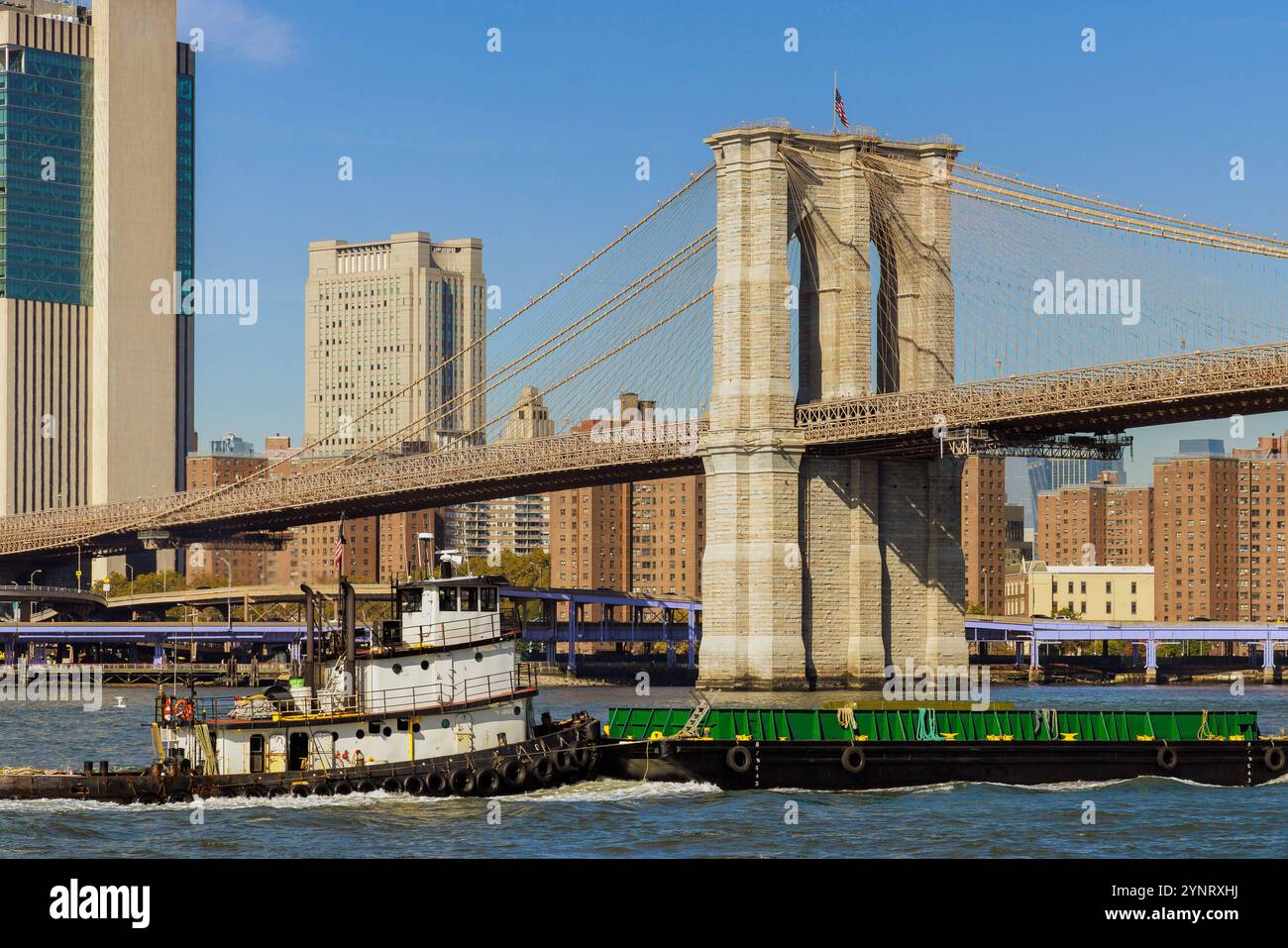 Tugboat navigates East River near Brooklyn Bridge, showcasing grand ...