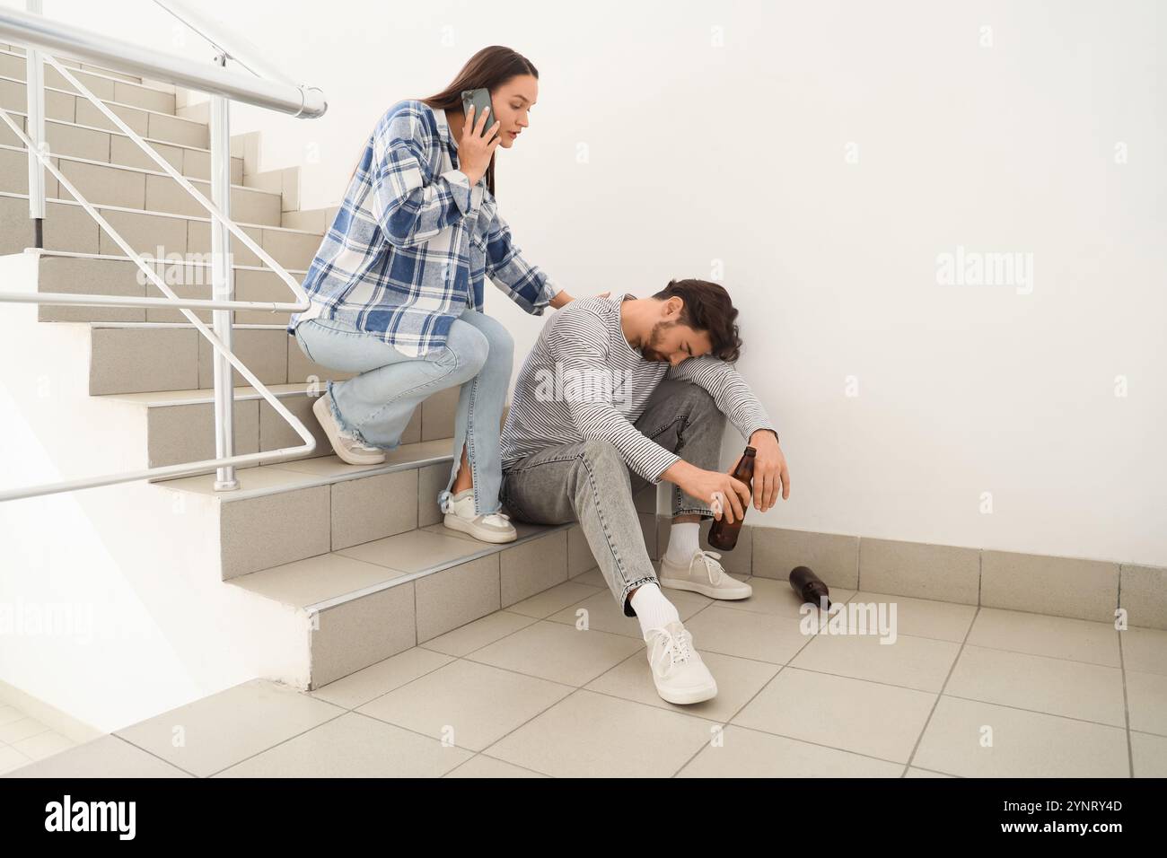 Woman calling an ambulance for drunk man sitting on stairs Stock Photo ...