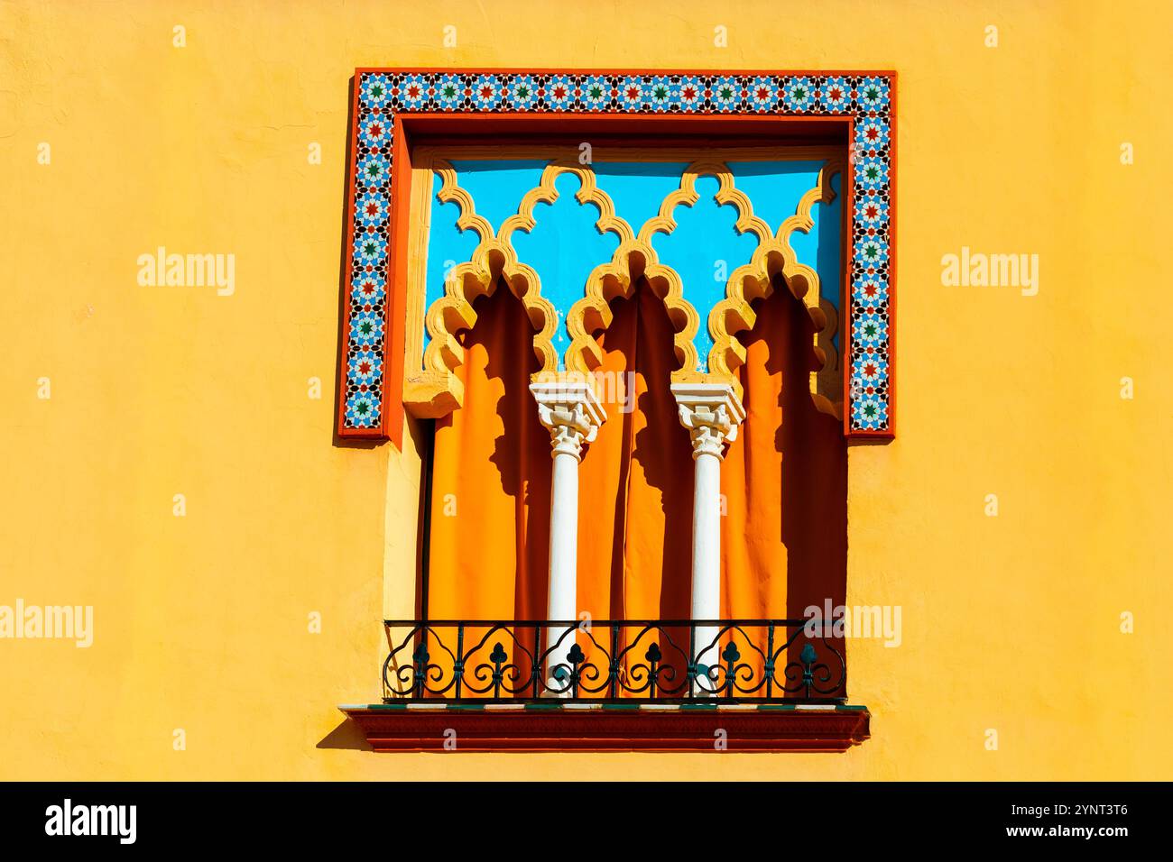 Ornately decorated window set in a bright yellow wall. Window features ...