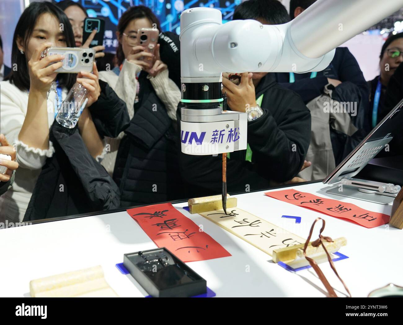Beijing, China. 26th Nov, 2024. Visitors observe a robot calligraphy ...