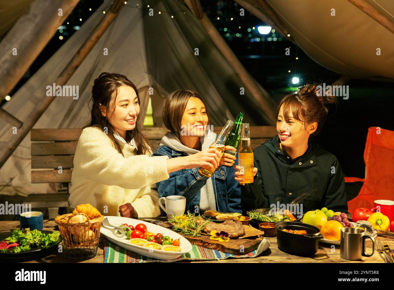 Three smiling women in their 20s having outdoor dinner Stock Photo - Alamy