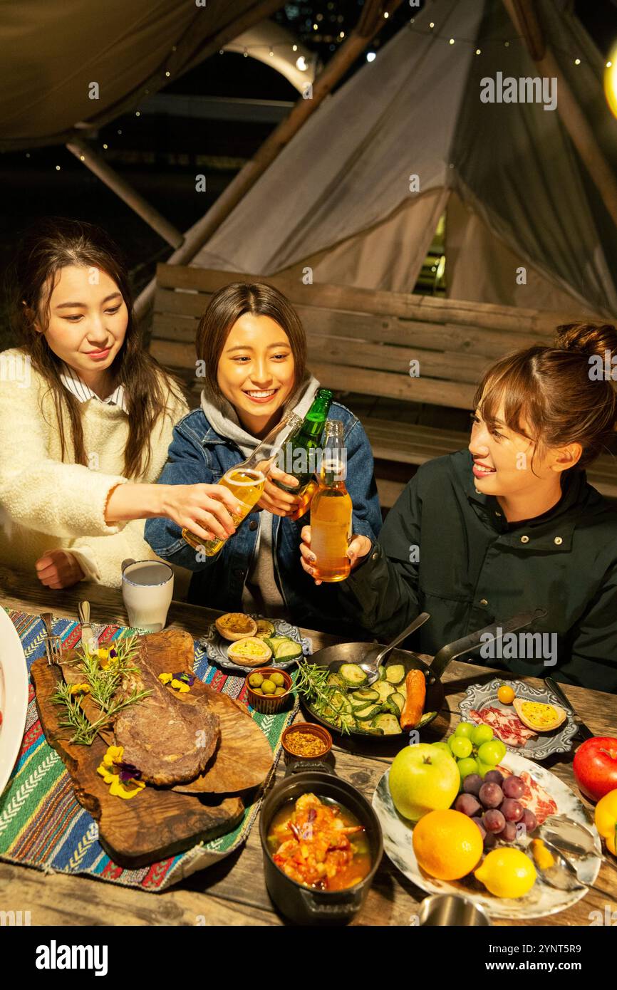 Three smiling women in their 20s having outdoor dinner Stock Photo - Alamy