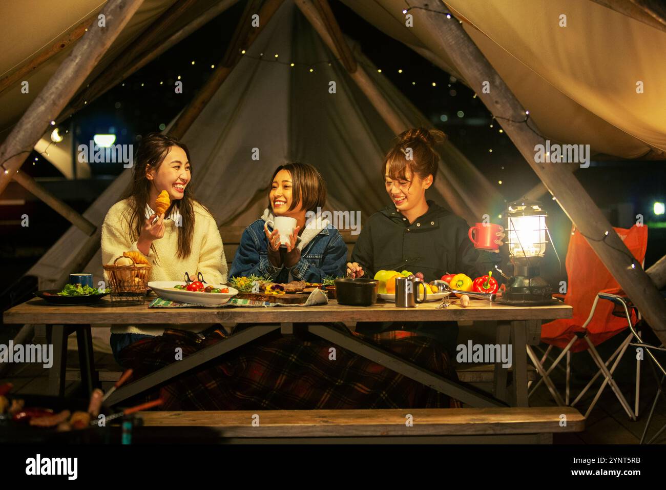 Three smiling women in their 20s having outdoor dinner Stock Photo - Alamy