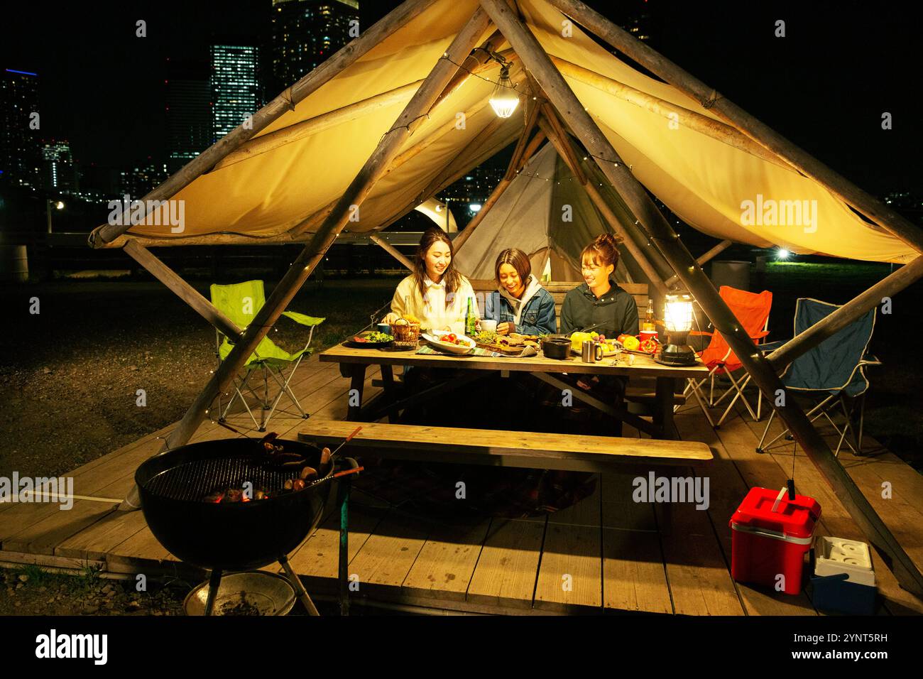 Three smiling women in their 20s having outdoor dinner Stock Photo - Alamy