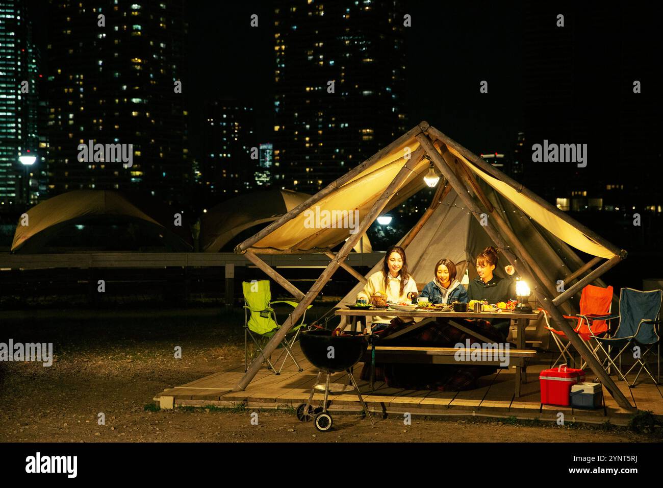Three smiling women in their 20s having outdoor dinner Stock Photo - Alamy
