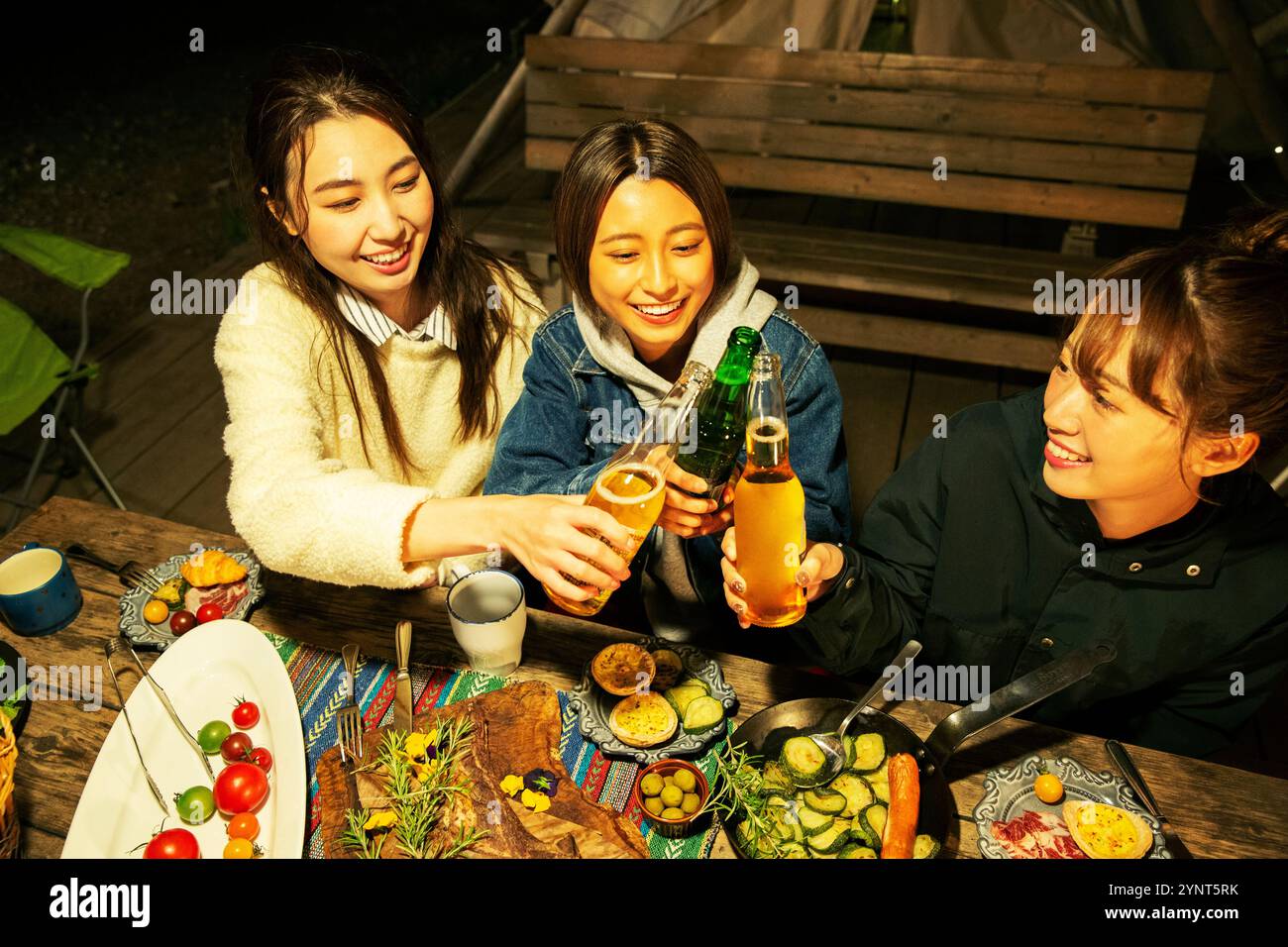 Three smiling women in their 20s having outdoor dinner Stock Photo - Alamy