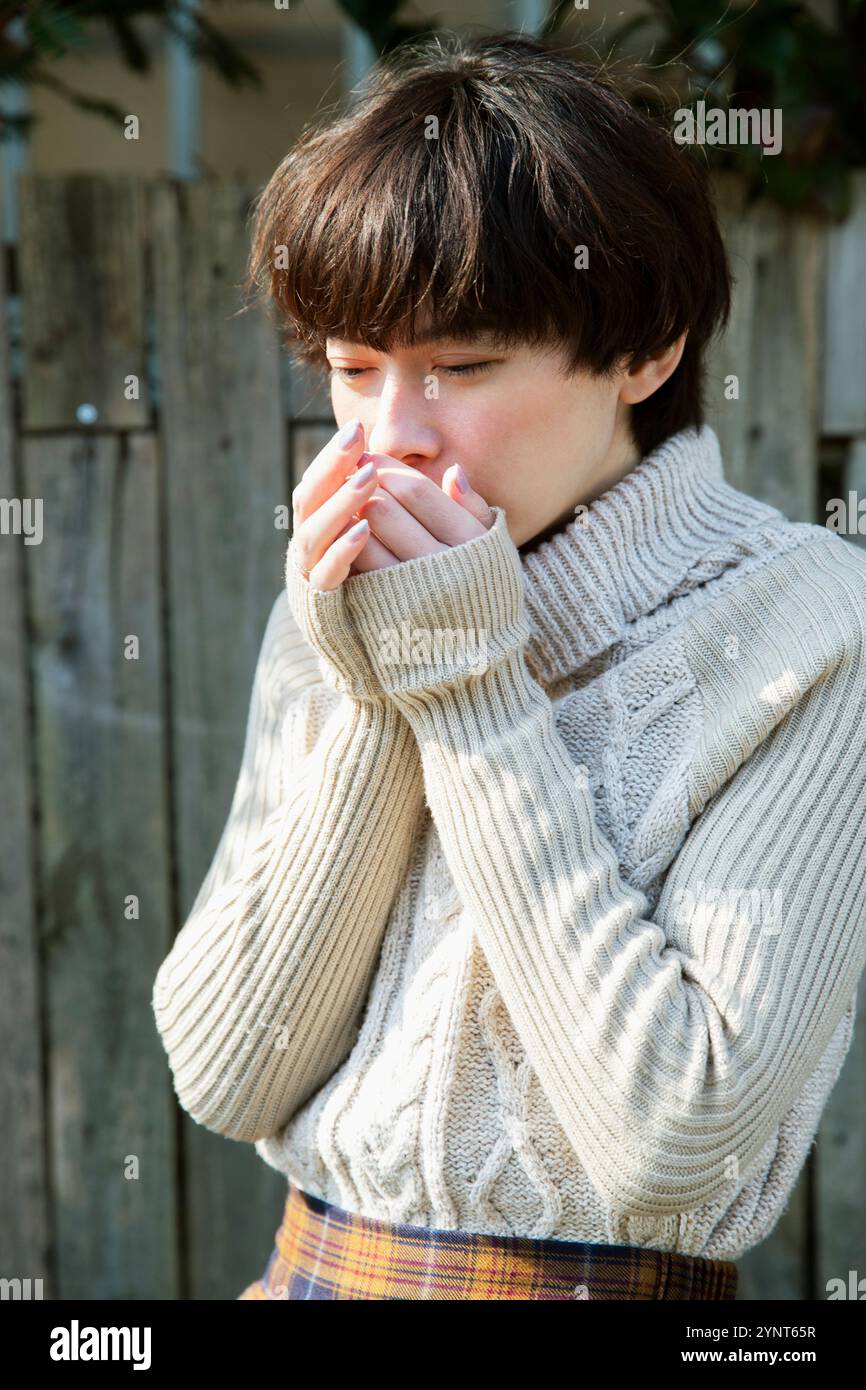 Woman in her 20s warming her biting hands Stock Photo - Alamy