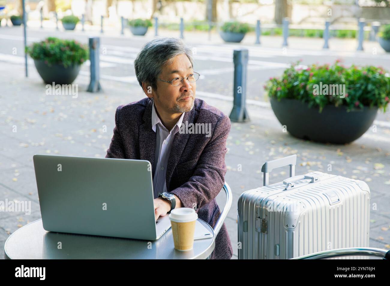 Man in his 60s using a computer on the terrace Stock Photo - Alamy