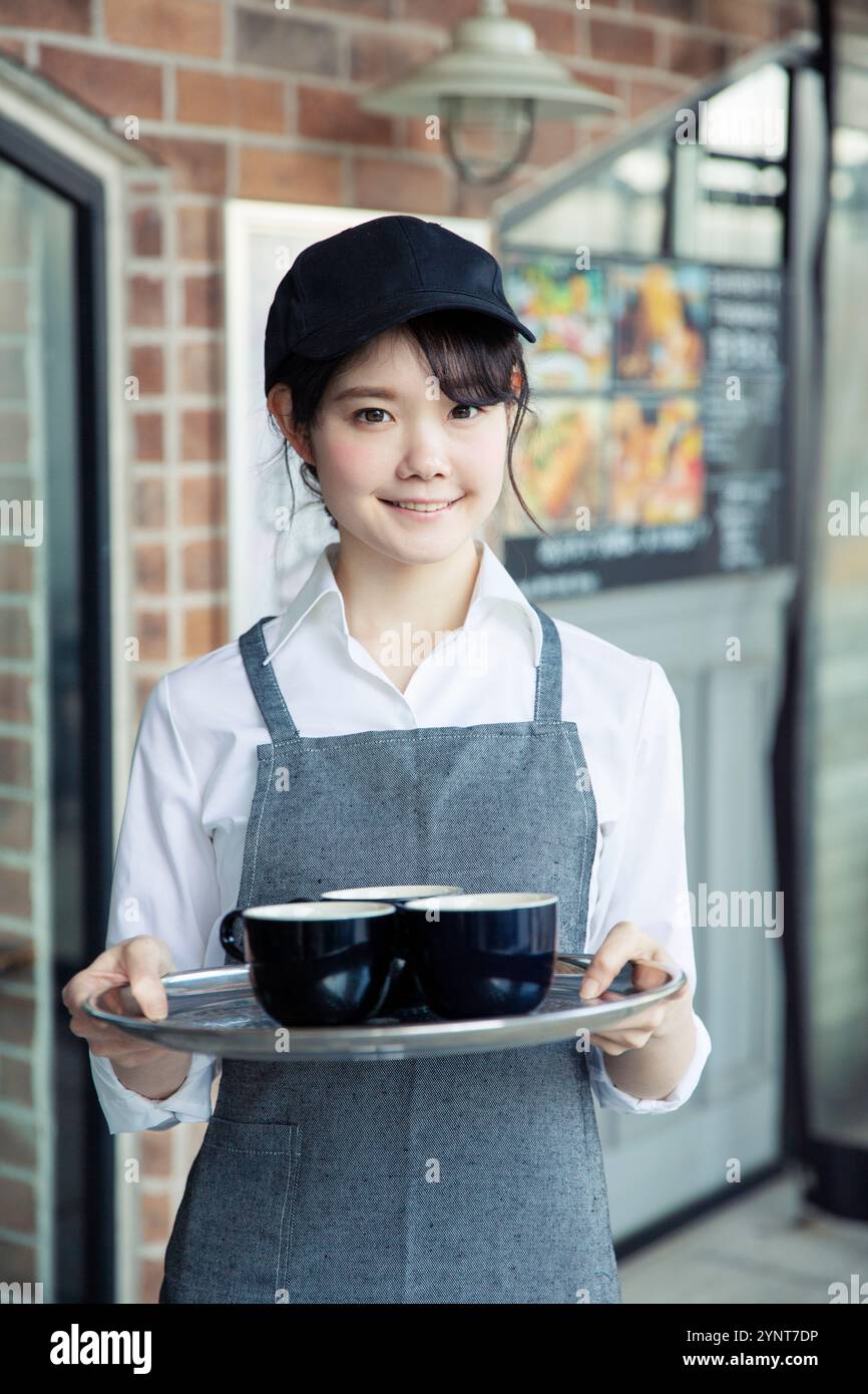 Female café worker in her 20s serving drinks Stock Photo - Alamy