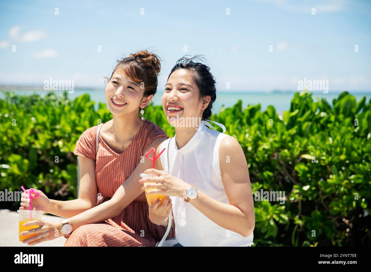 Two women in their 20s sitting on a bench talking Stock Photo - Alamy
