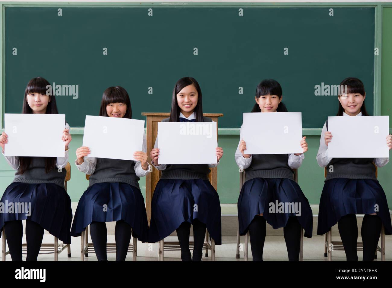 Female students sitting in a row holding a board in a classroom Stock ...