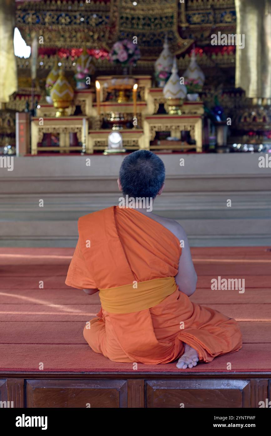 A young Thai Buddhist novice monk sitting respectfully In front of a ...