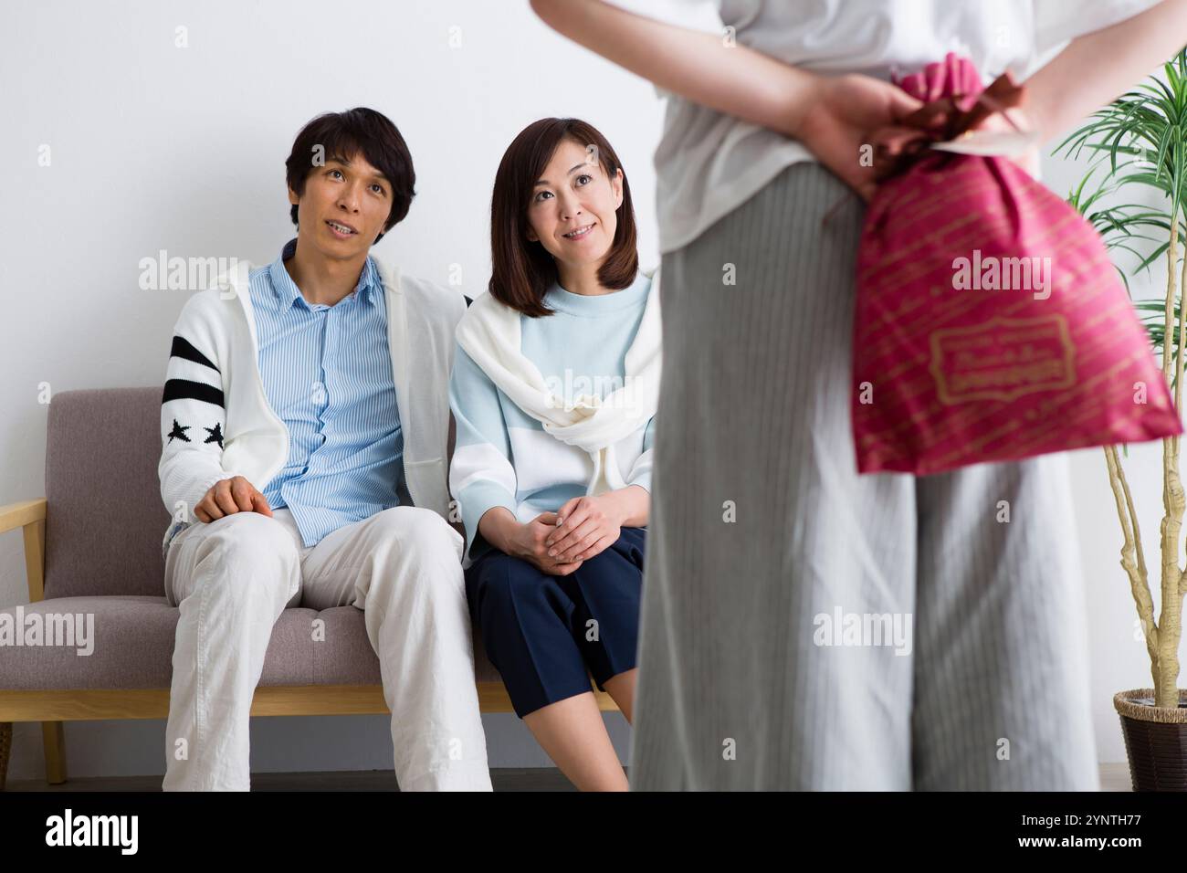 Parents and daughter holding hidden presents Stock Photo - Alamy