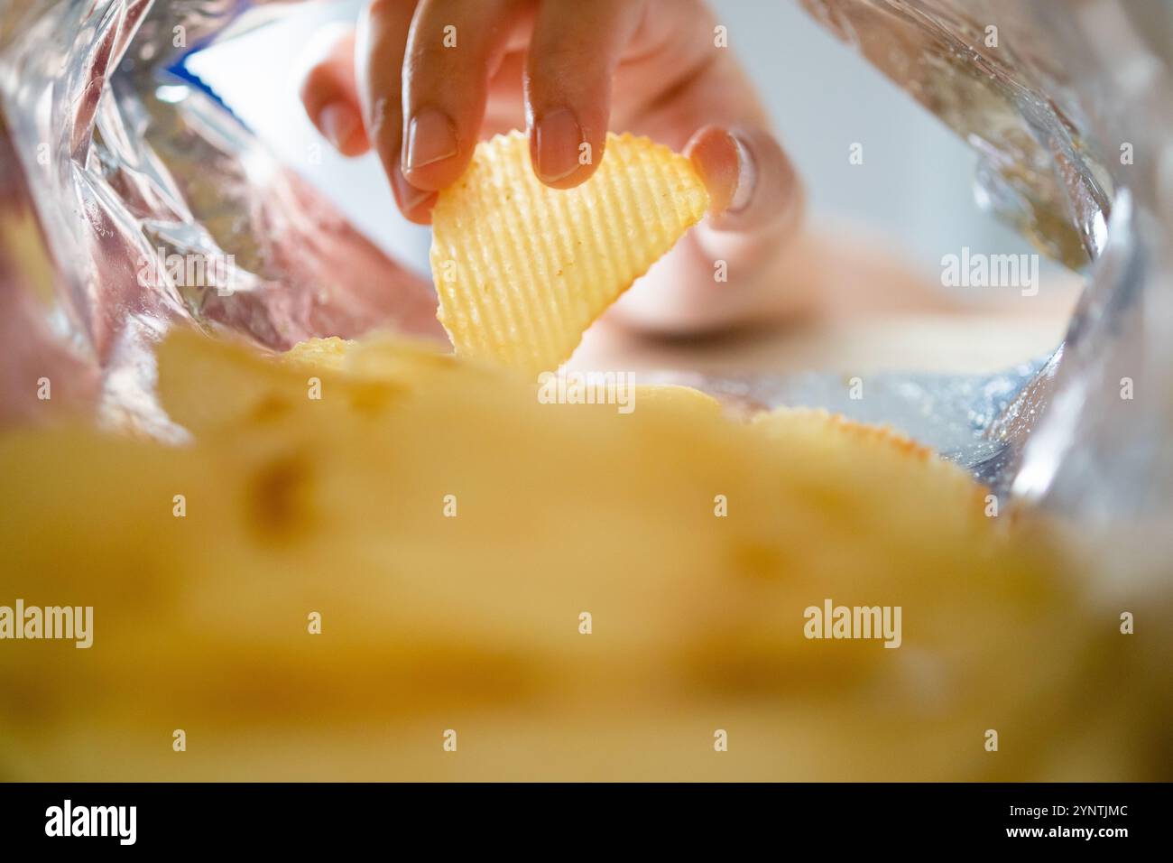 Hand picking potato chips inside snack bag Stock Photo - Alamy