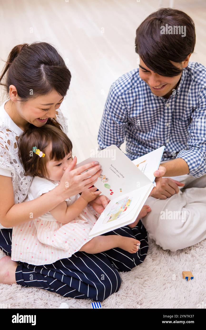Family reading a book to their child Stock Photo - Alamy
