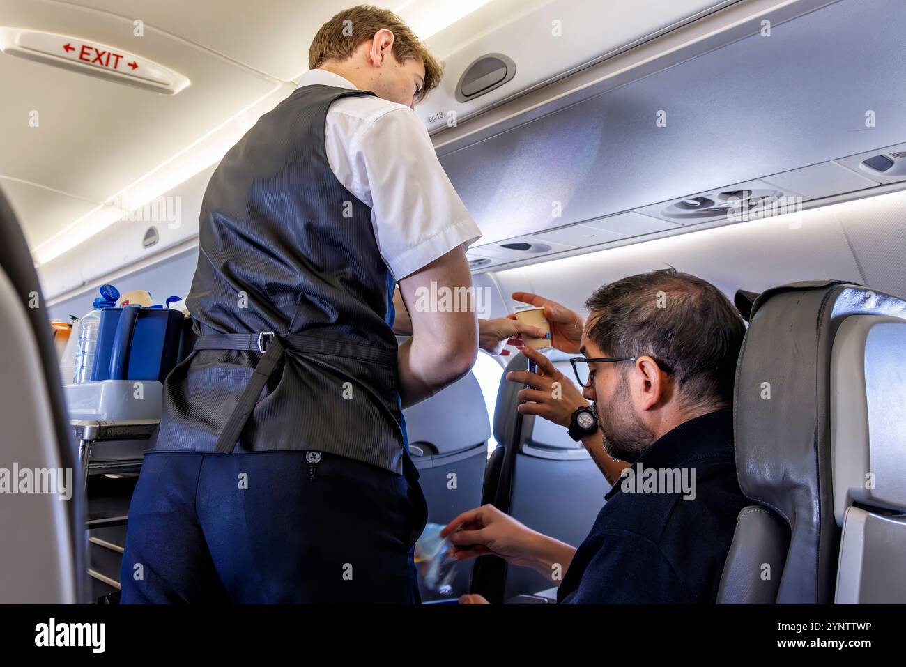 Cabin interior, crew serving drinks onboard flight from UK to Amsterdam ...