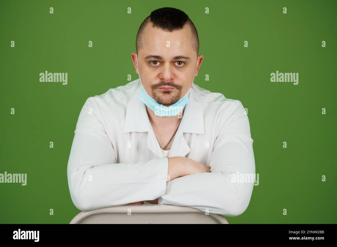 Confident Medic in Laboratory Coat with Medical Mask Against Green ...
