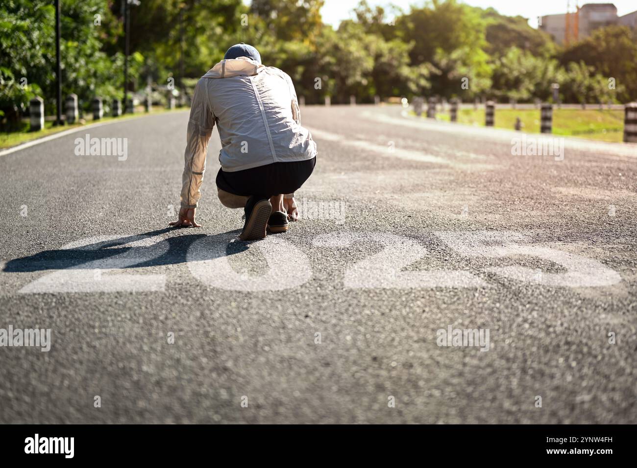 Runner crouching in a starting position on road with the numbers 2025 ...