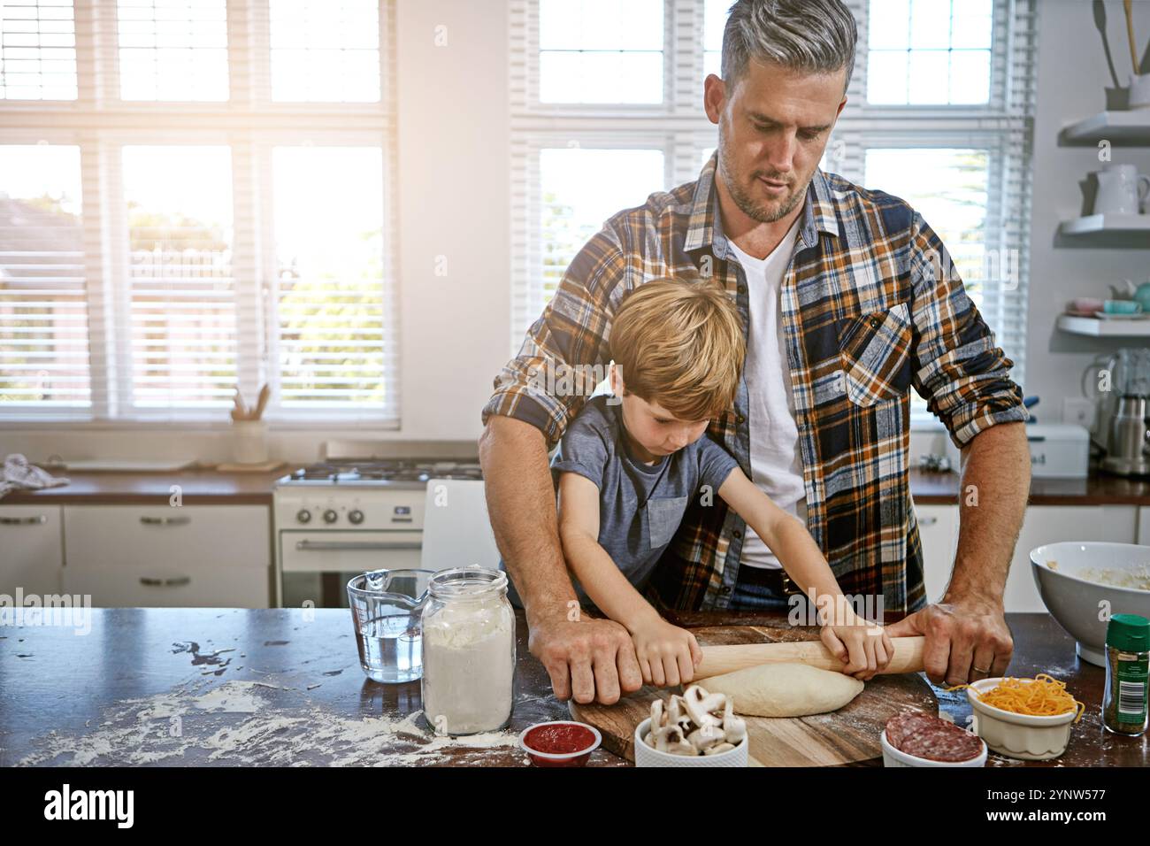 Father, child and cooking in kitchen for teaching with pizza, toppings ...