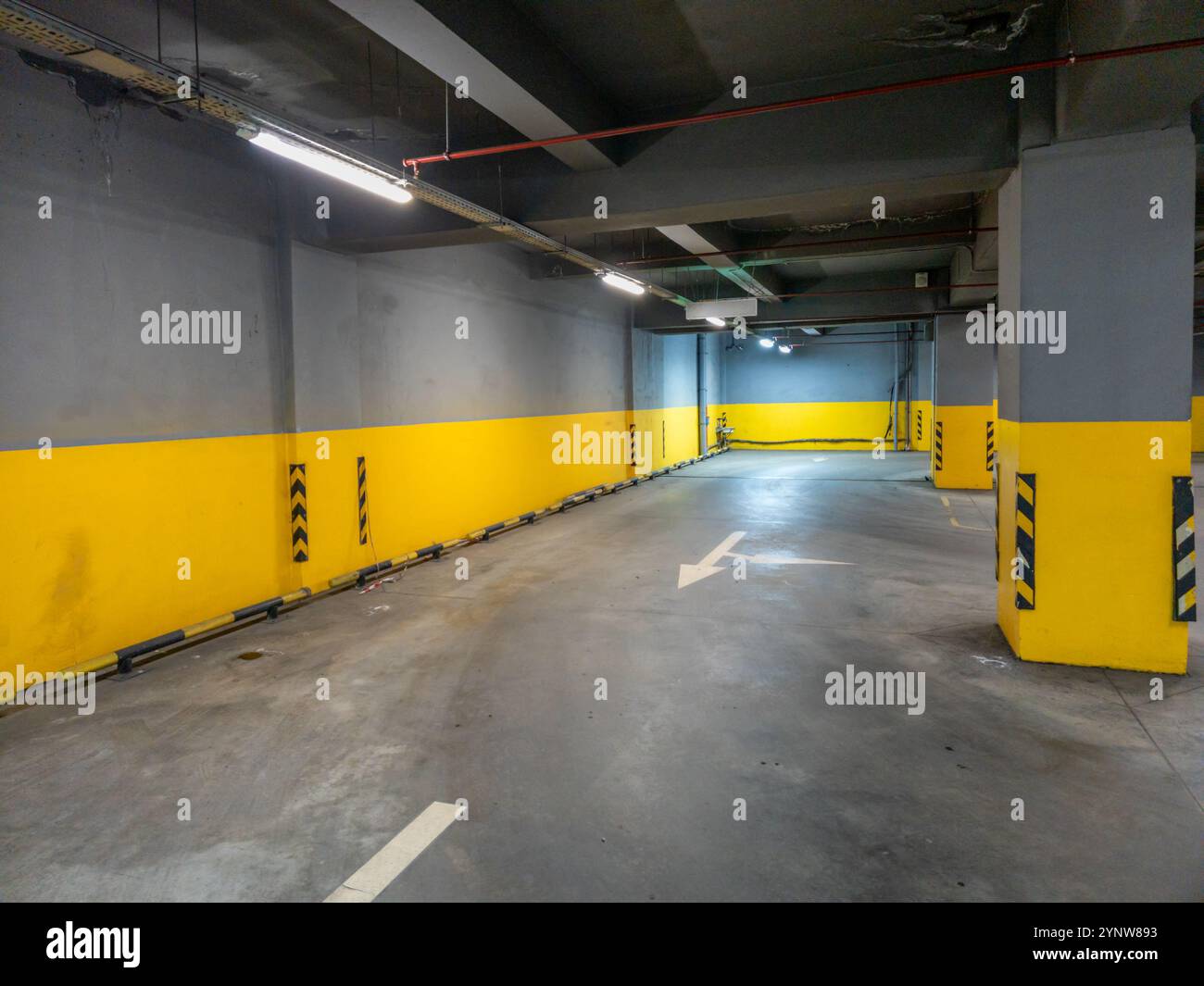 A spacious and well lit underground parking garage features bright ...
