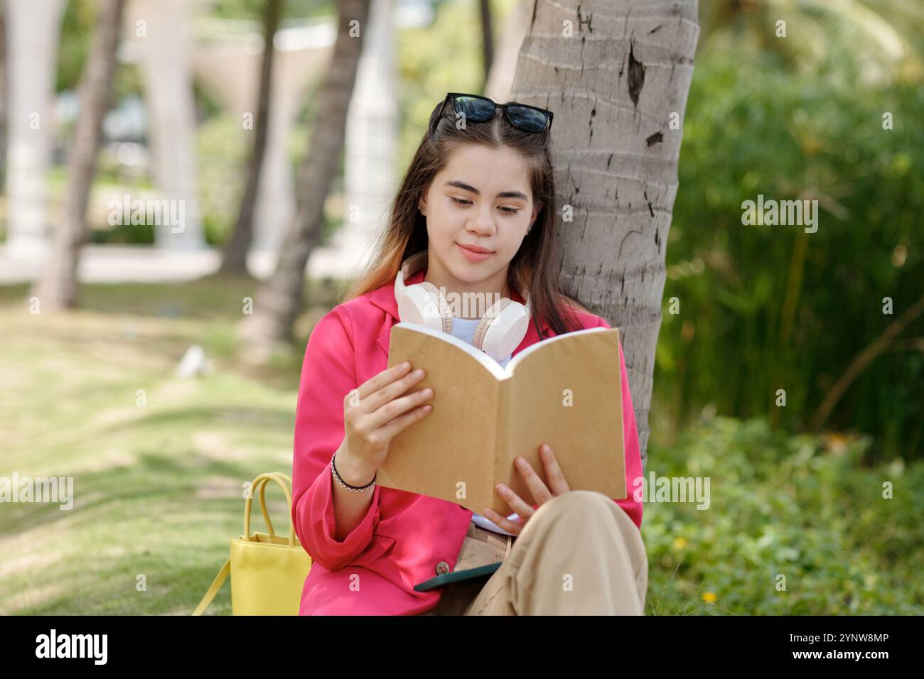 Reading Book Under Tree With Sunglasses and Headphones Stock Photo - Alamy