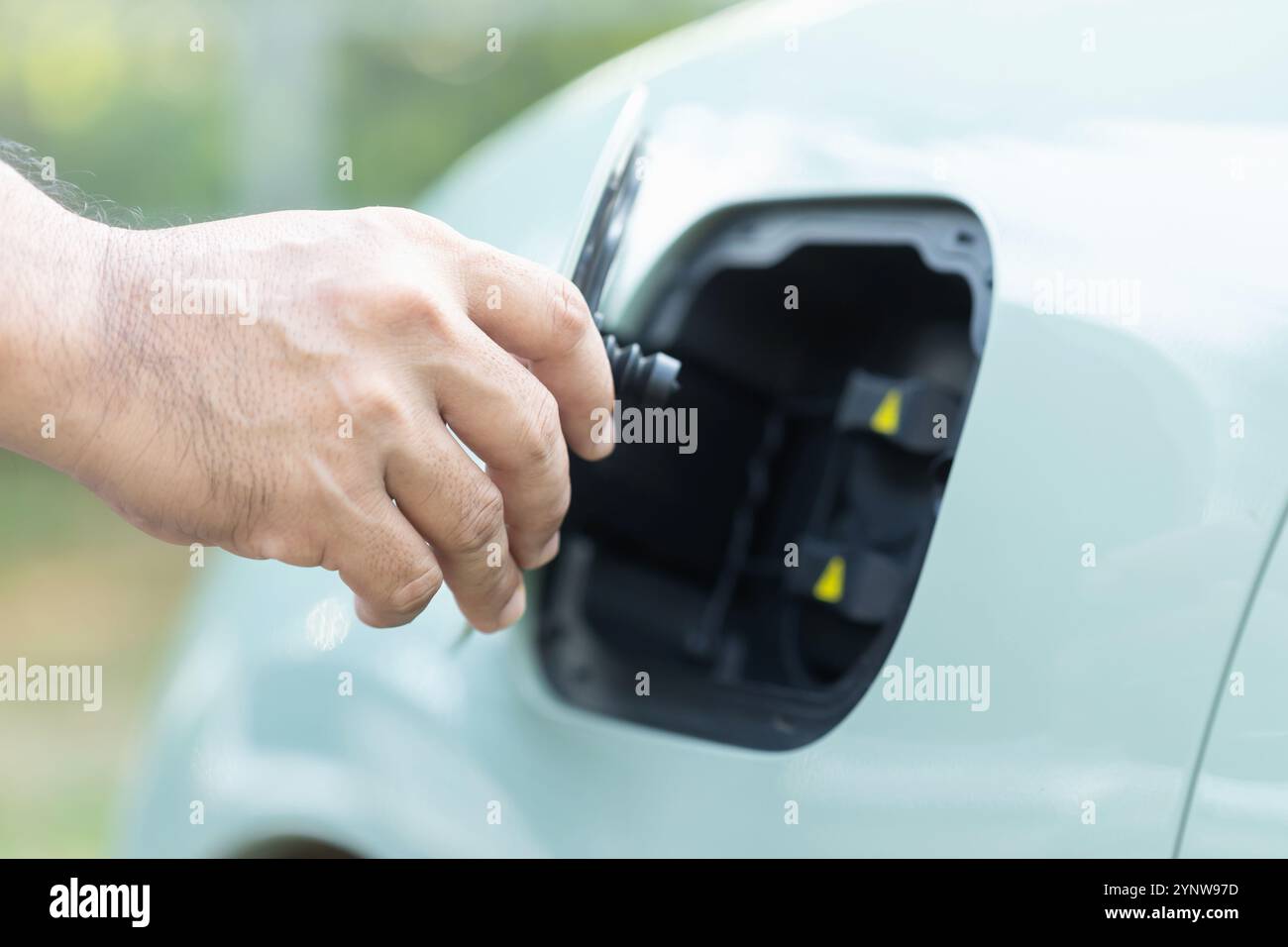 Car owner's hand gently touches the charging port cover of an electric ...