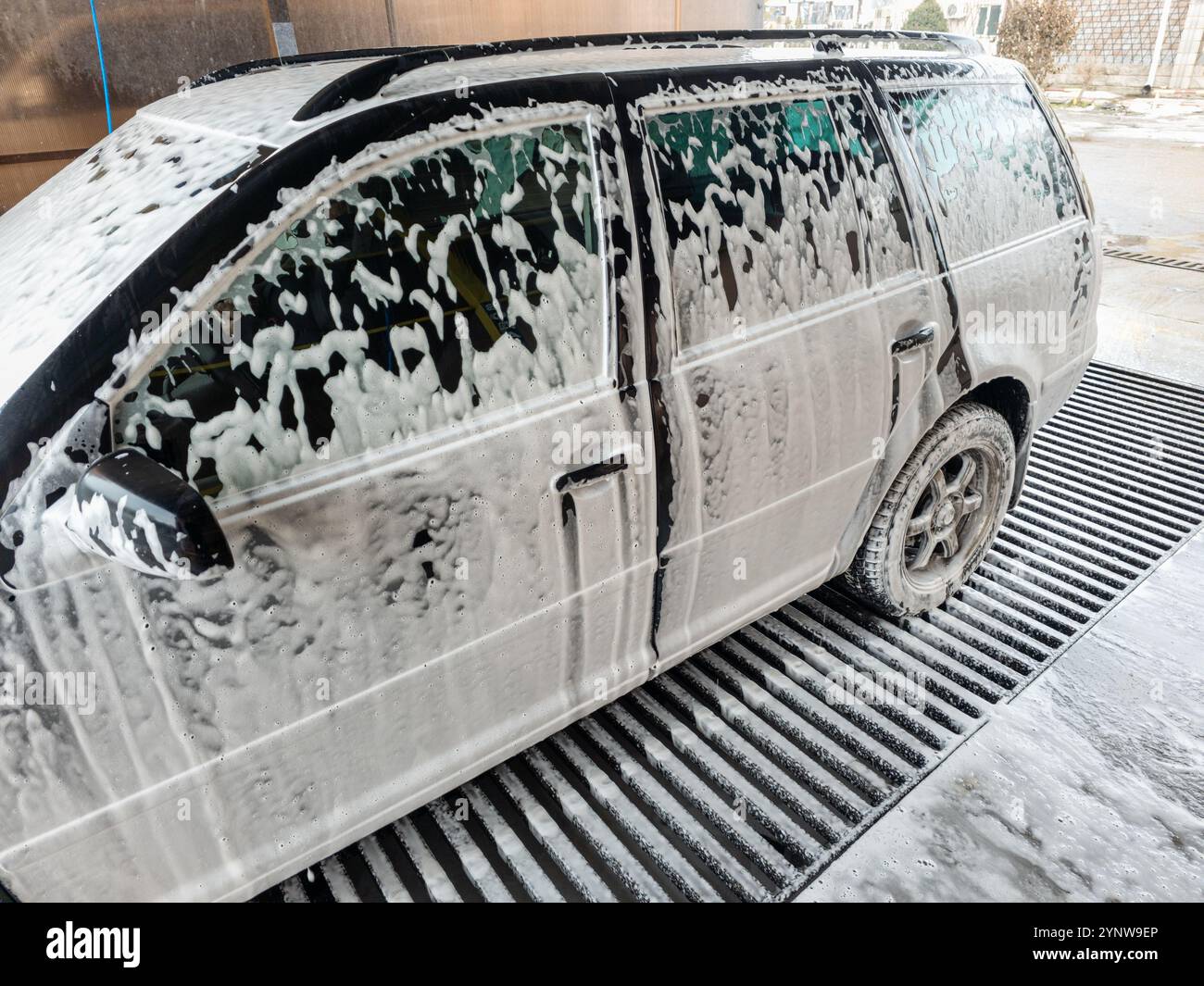 A car is covered in a thick foam layer during a wash in a public self ...