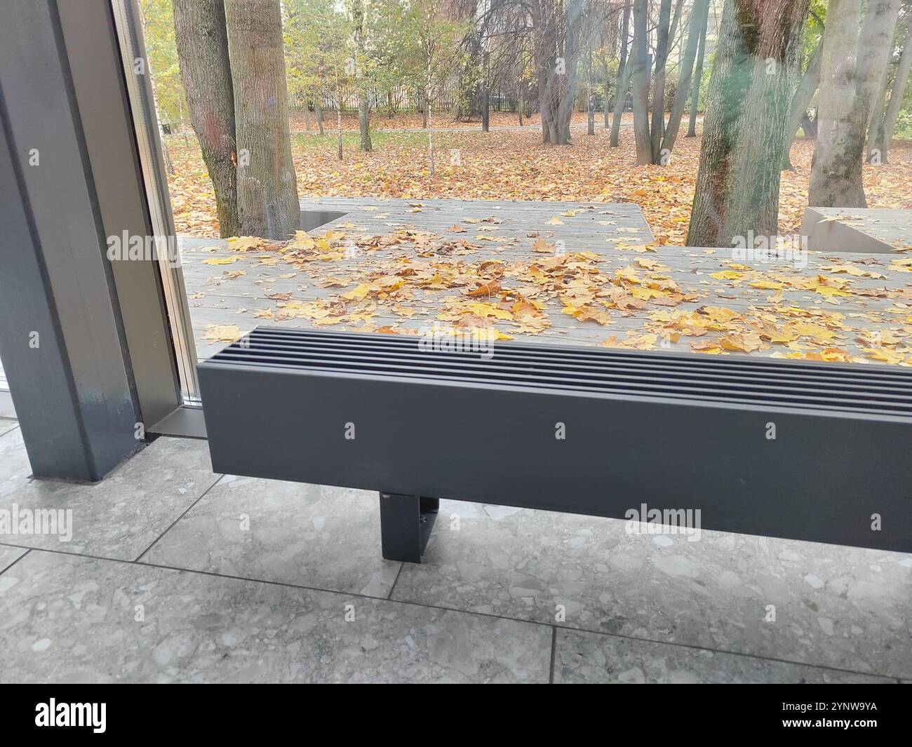 A sleek heating unit by a glass wall, with a tranquil park scene in the ...