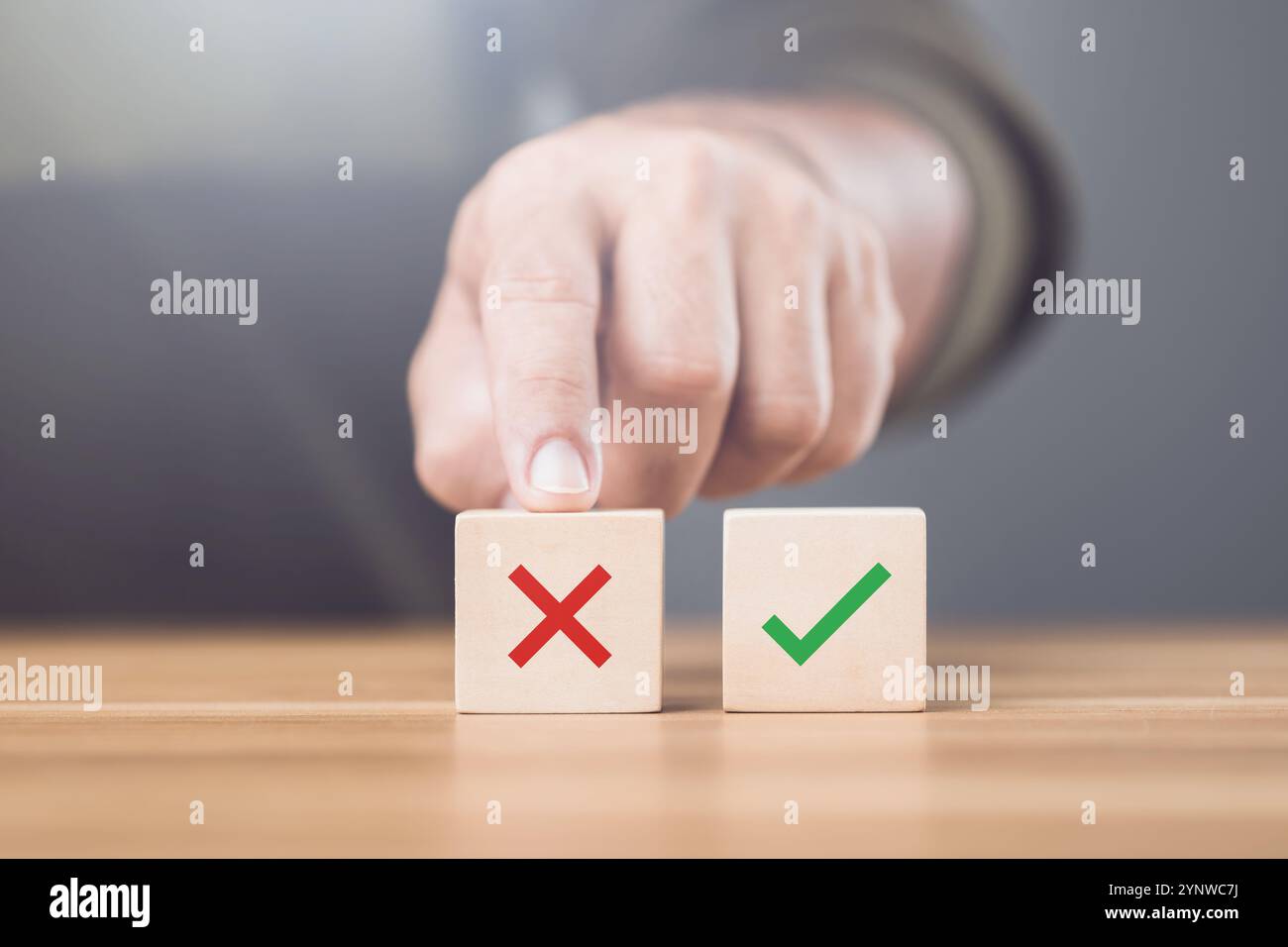 Man choosing between a checkmark and an 'X' symbol on wooden blocks ...