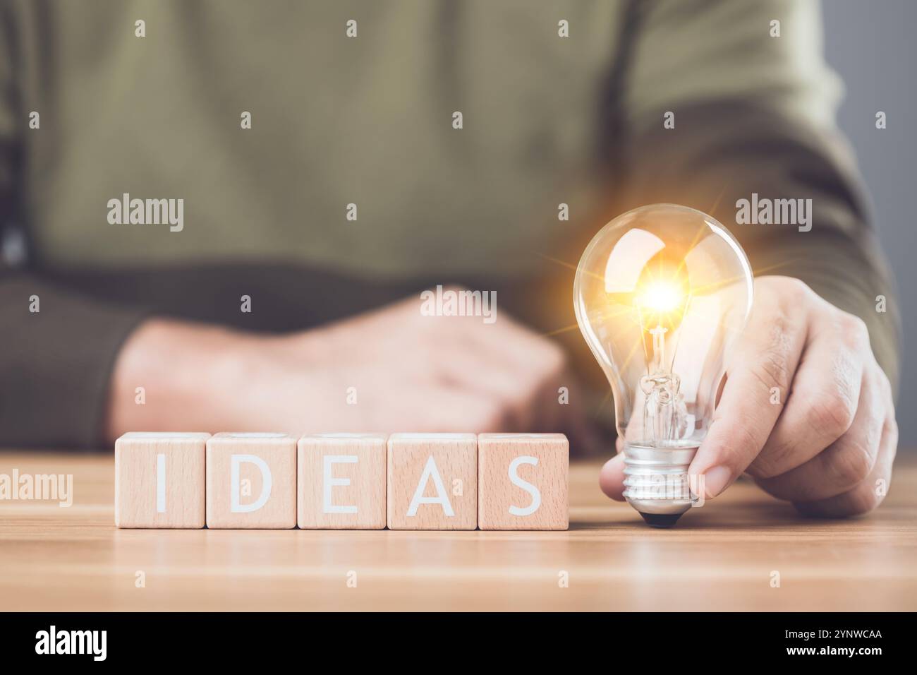 A light bulb next to wooden letters spelling 'IDEAS' arranged on a ...