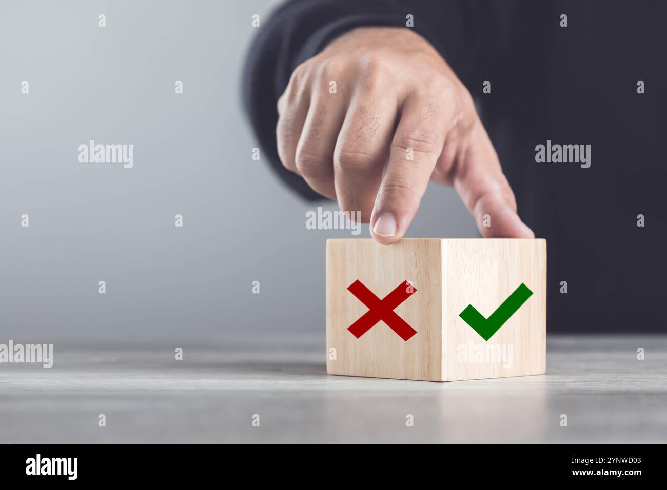 Man choosing between a checkmark and an 'X' symbol on wooden blocks ...