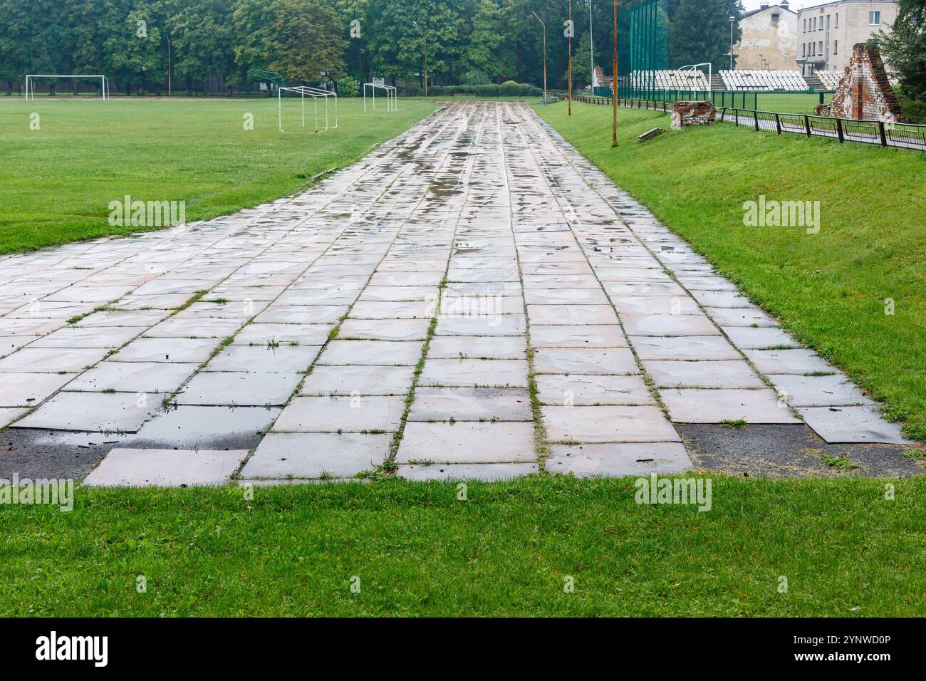 Old damaged running track in stadium with faded white lines and broken ...