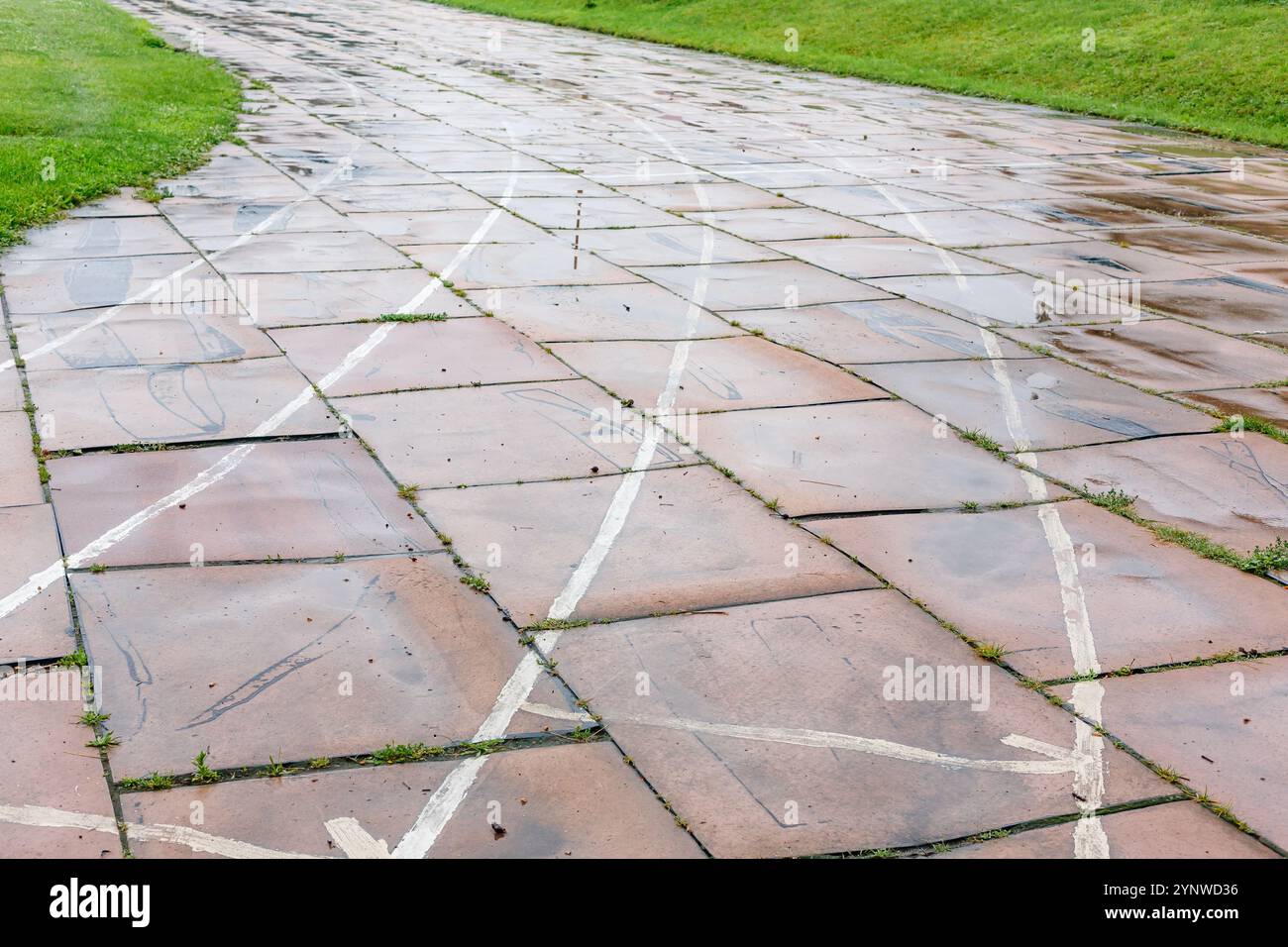 Old damaged running track in stadium with faded white lines and broken ...