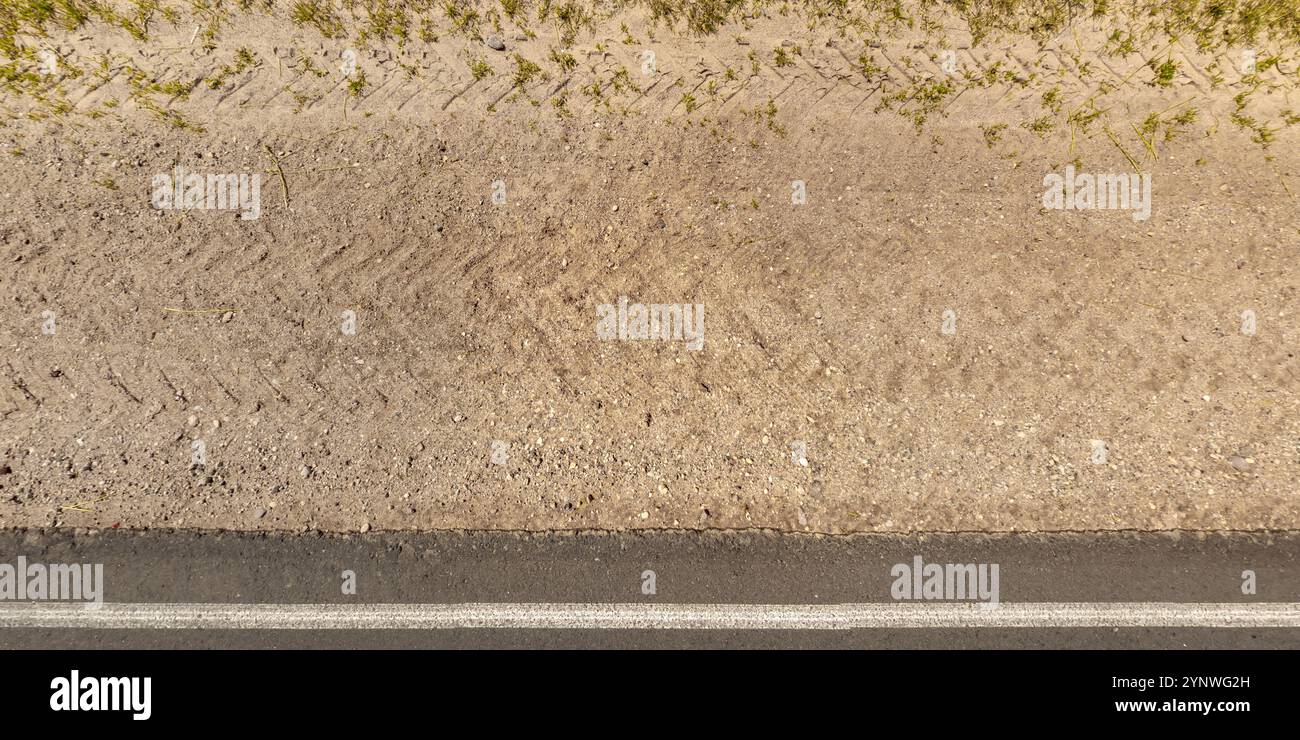 view from above on texture of asphalt road with median from gravel road ...