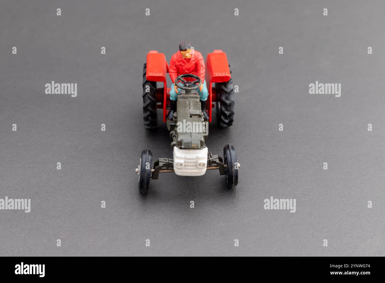 Toy tractor scale model with driver on grey background with copy space ...