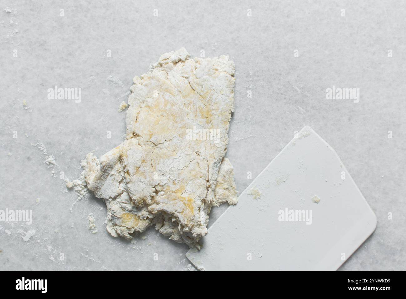 Overhead view of flour and egg being mixed on a white countertop, top ...