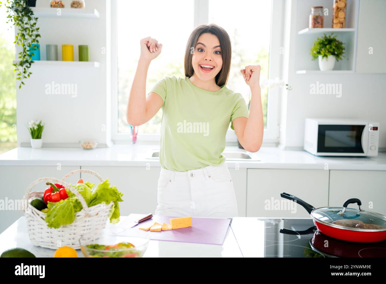 Joyful young woman girl celebrating in modern kitchen while cooking ...